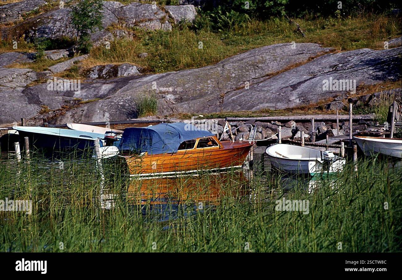 Boats at a jetty in front of a rock face in an archipelago in Sweden ...