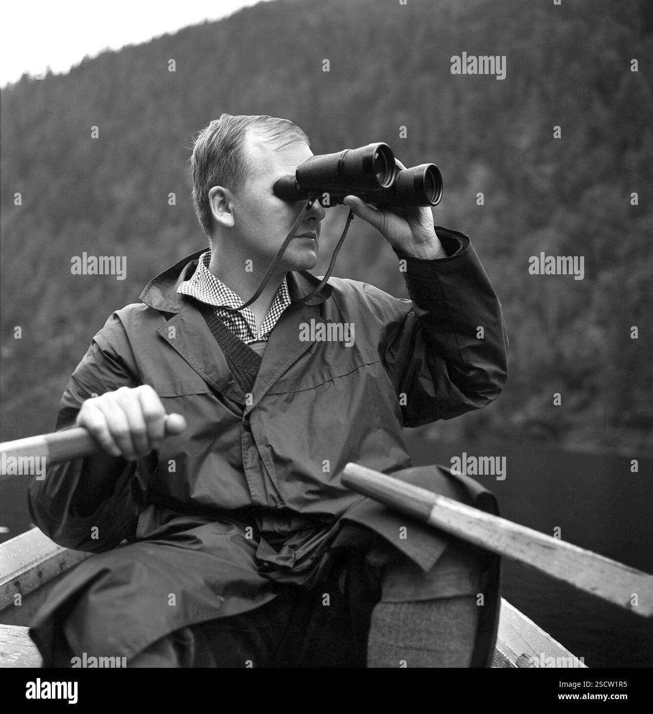 A man sits in a rowing boat on Lake Toplitz in Styria and looks through ...