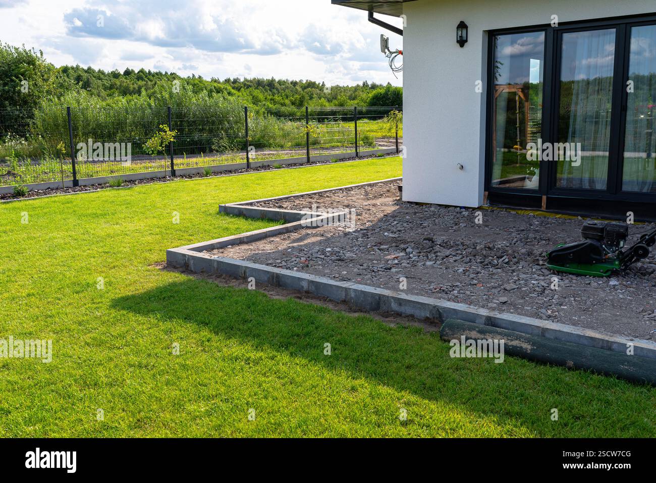 A man compacts rubble on a terrace under construction using a hand-held ...