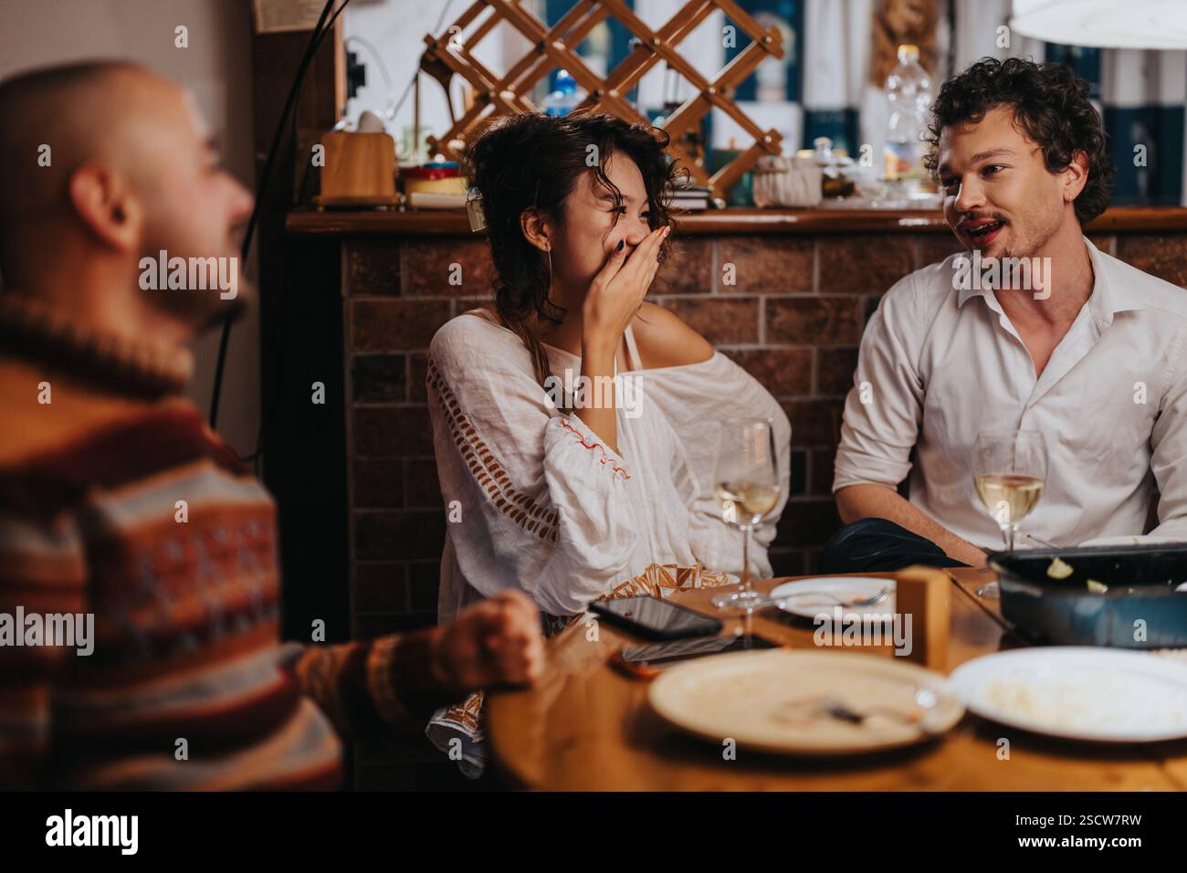 Friends enjoying laughter and conversation over wine in a cozy setting ...