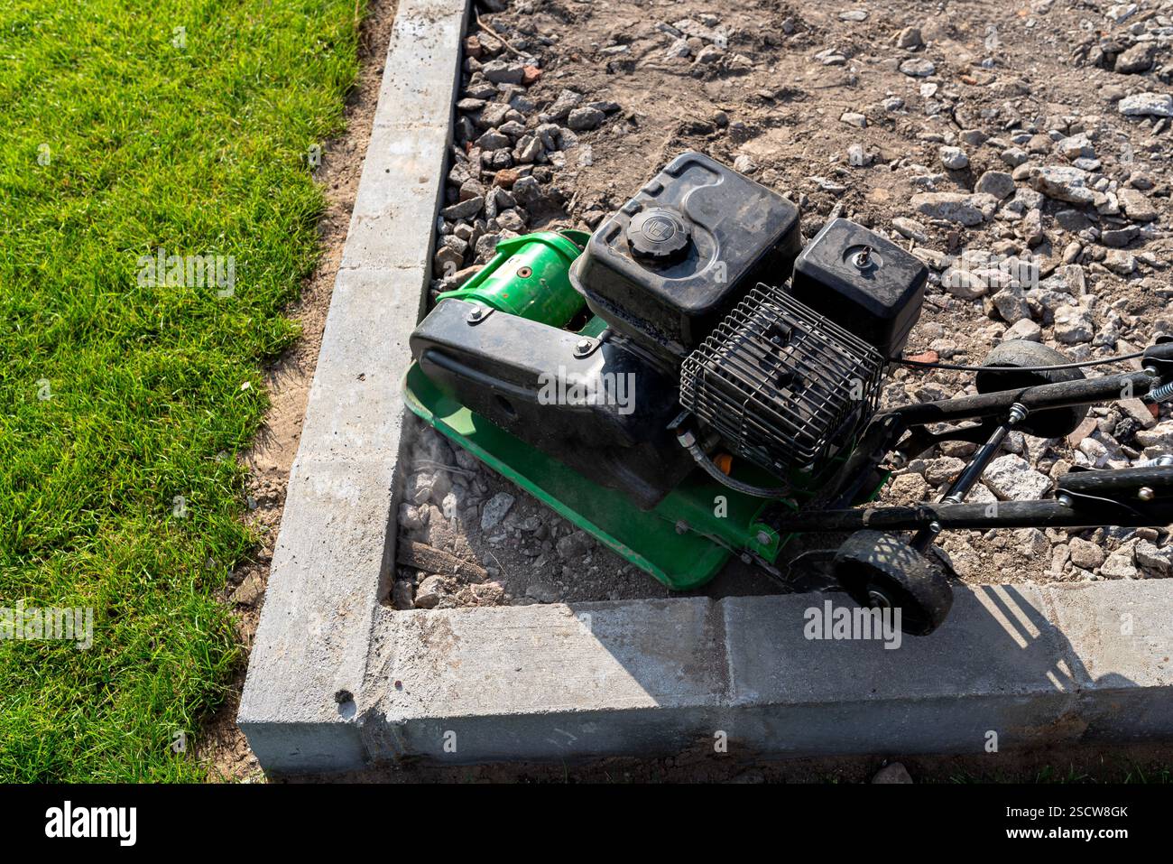 A man compacts rubble on a terrace under construction using a hand-held ...