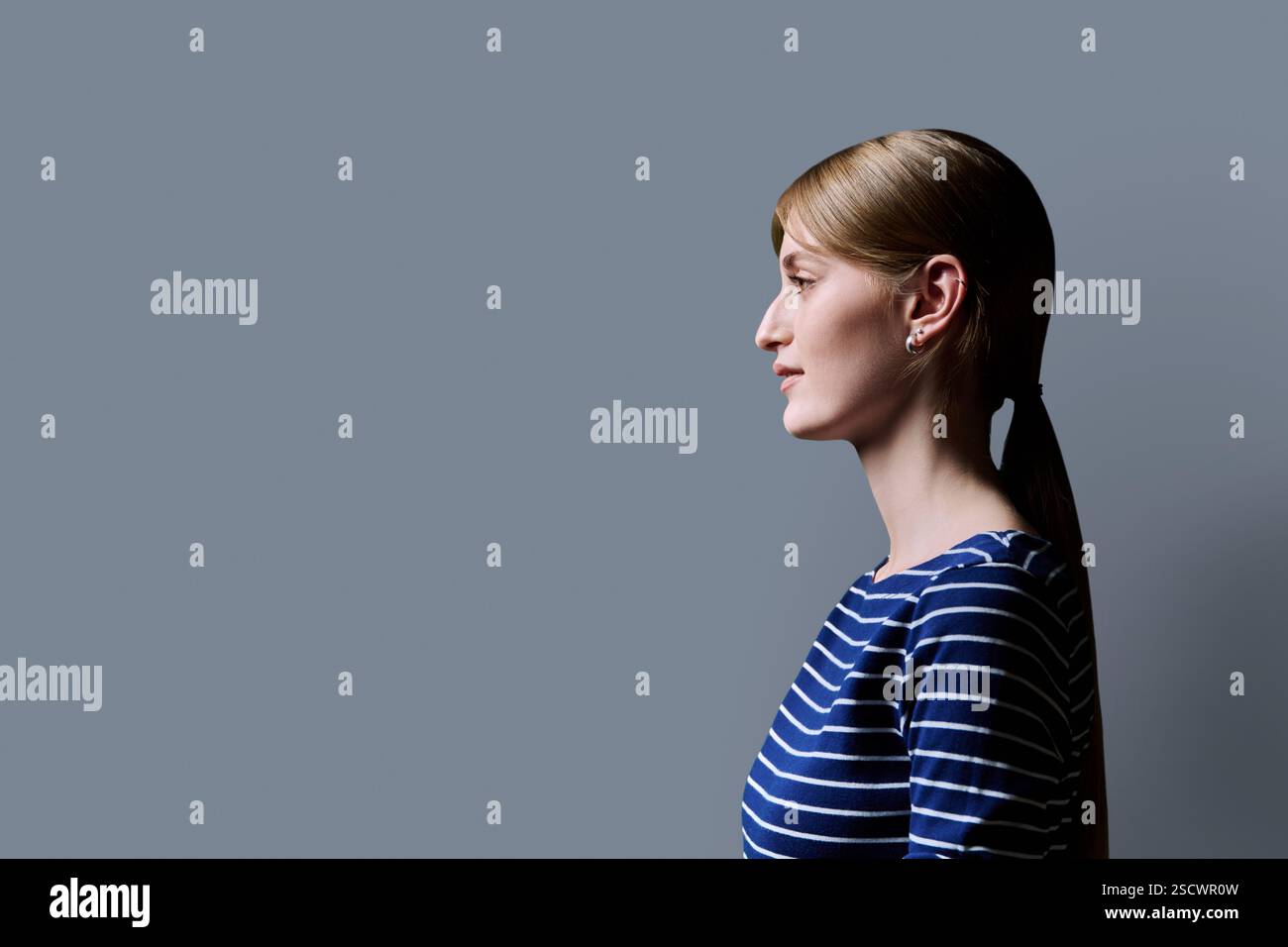 Profile view, young smiling female looking forward on gray studio ...