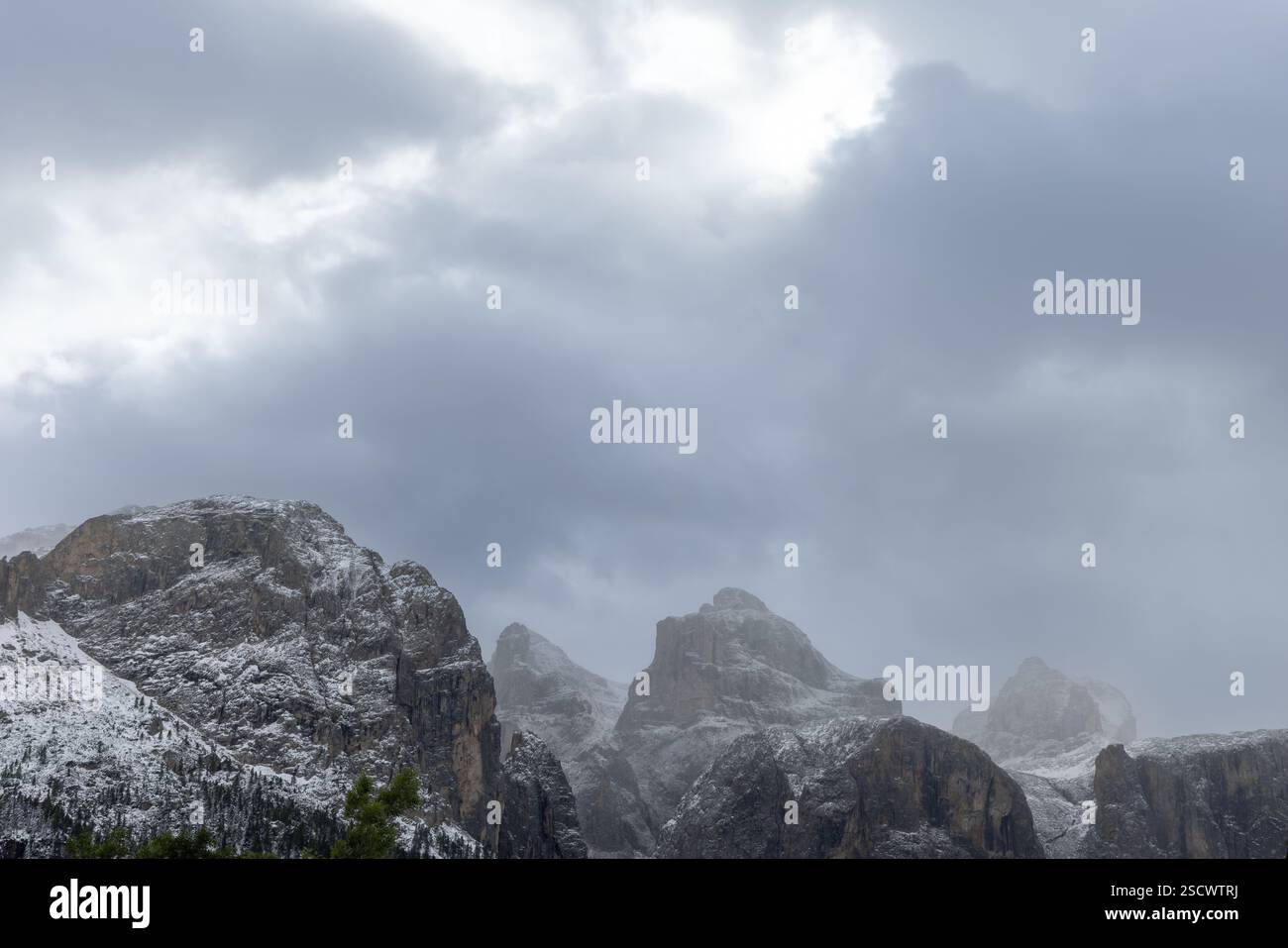 Dolomite mountains are enveloped in an overcast sky, with patches of ...