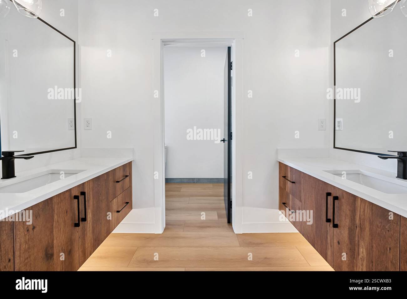 The bathroom is very clean and well-lit. The two sinks are white and ...