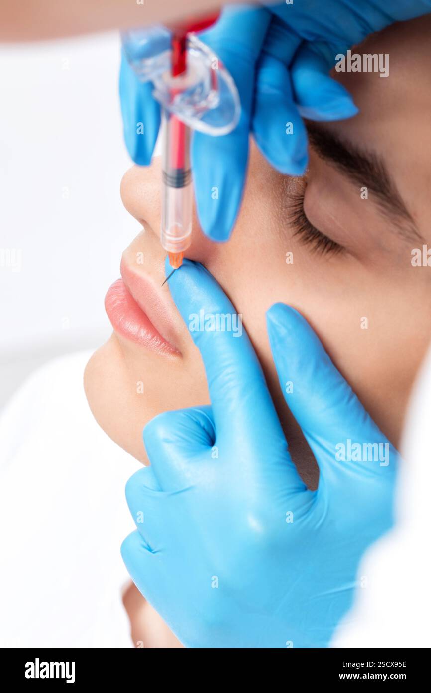 The cosmetologist makes injections for lip augmentation and anti ...