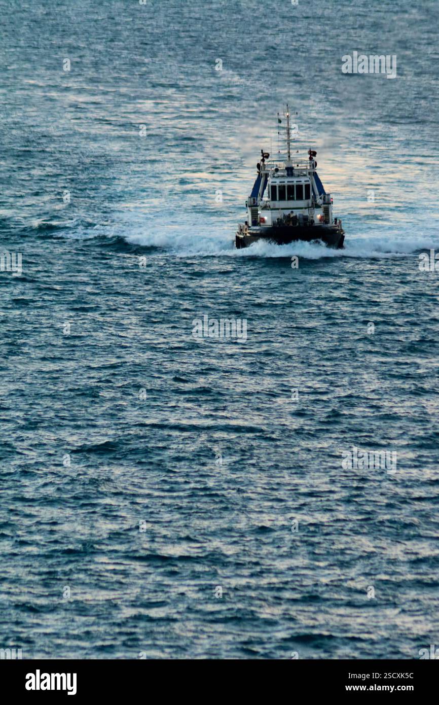 Civitavecchia. Italy - February 07, 2025: A workboat speeds through the sea, producing waves ...