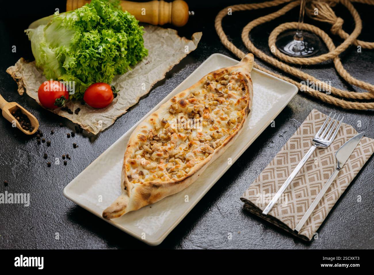 Turkish pide with diced chicken, cheese, and vegetables on plate in ...
