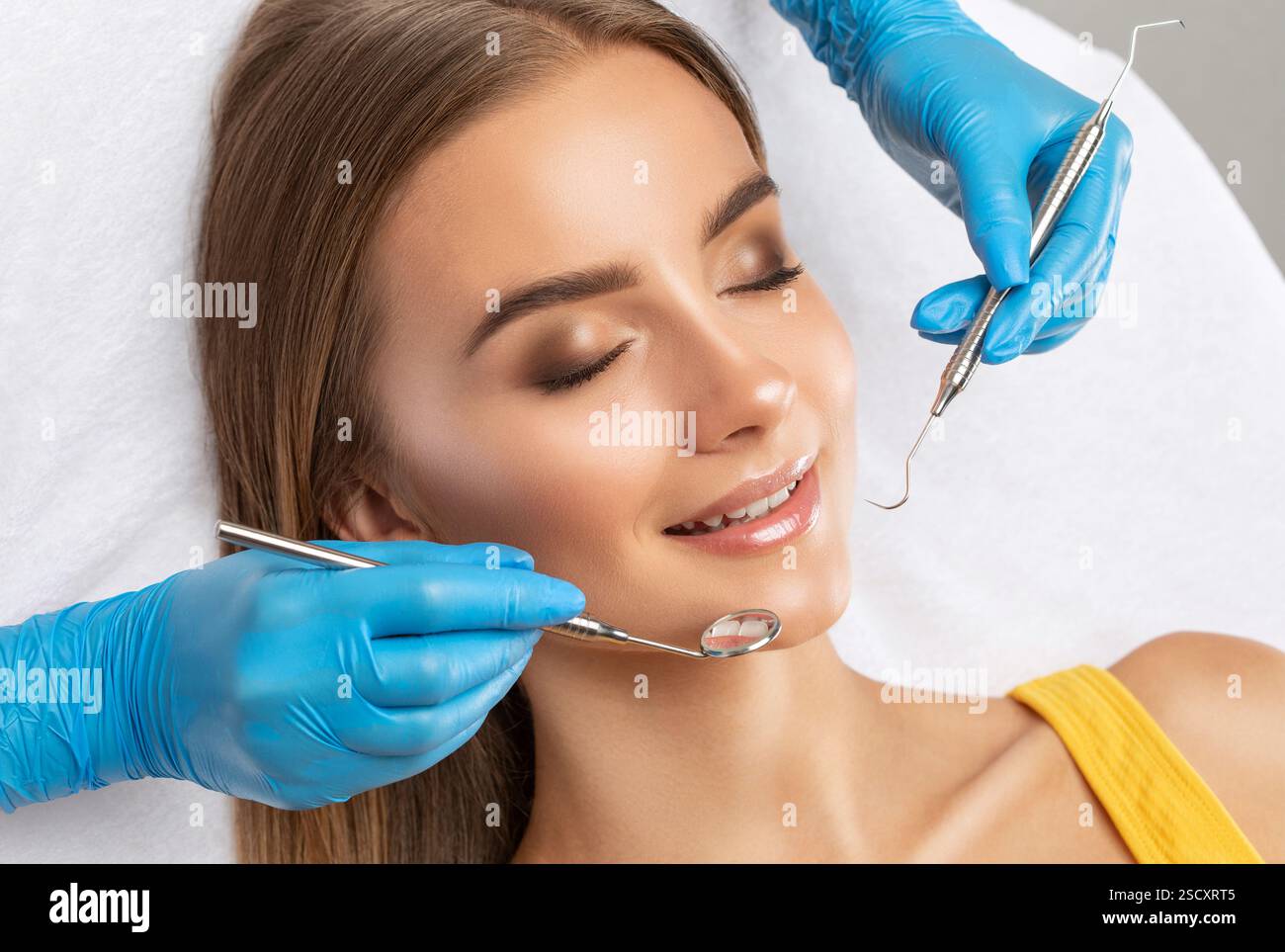 A dentist doctor treats caries on a tooth of a young beautiful woman in ...