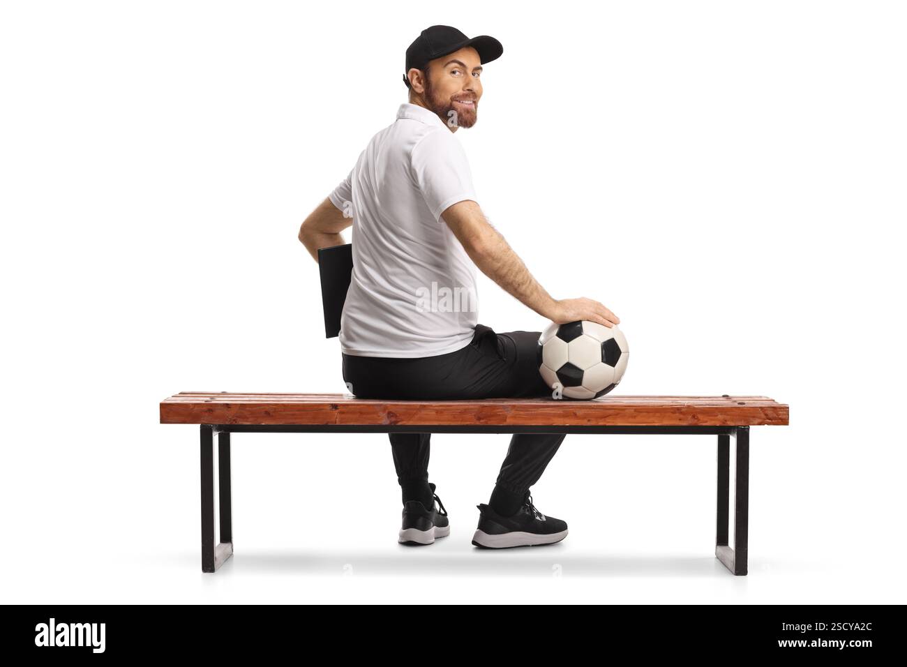 Football coach holding a ball and sitting on a bench isolated on white ...