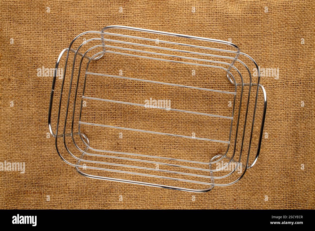 One wicker basket made of metal wire on jute canvas, close-up, top view ...