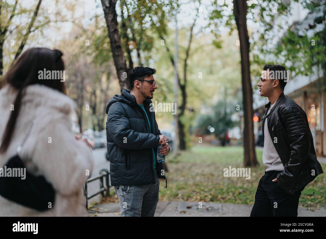Friends conversing outdoors on a stroll through a scenic park setting ...