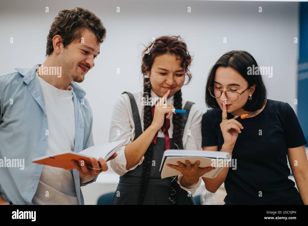 Three students collaborating on a school project in classroom Stock ...