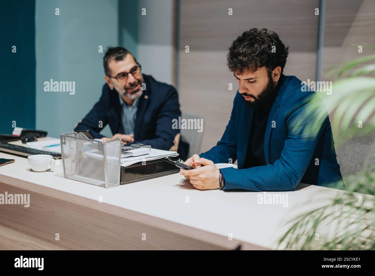 Two colleagues working together at a desk in a modern office setting ...
