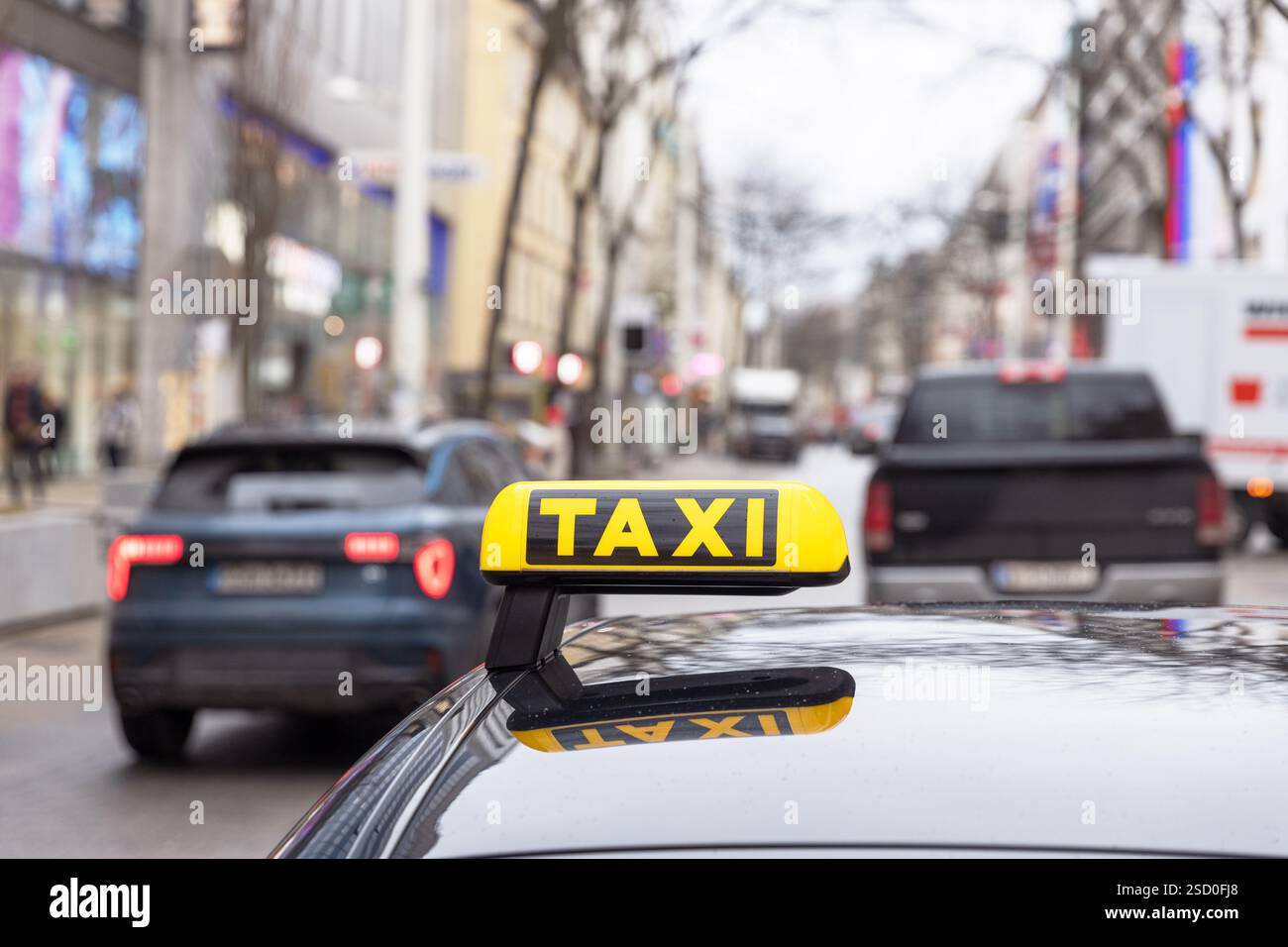 Urban street scene featuring a taxi sign in focus and vehicles in a ...