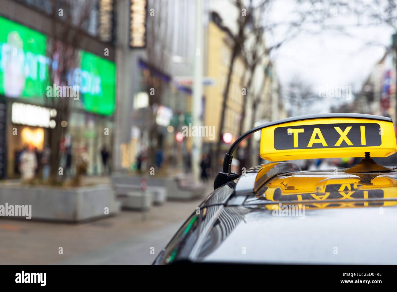 Bright yellow taxi cab with illuminated sign parked on a bustling city ...