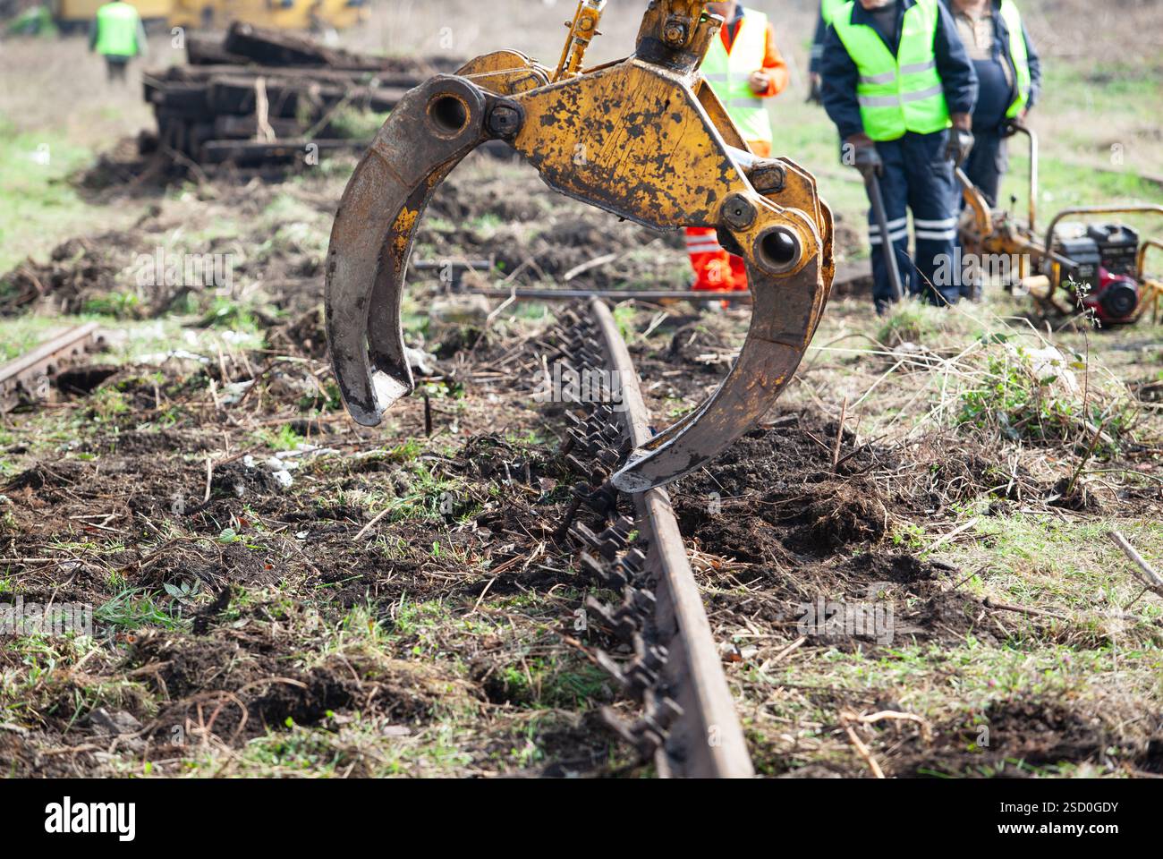 Industrial machinery lifting and removing old railroad tracks while ...