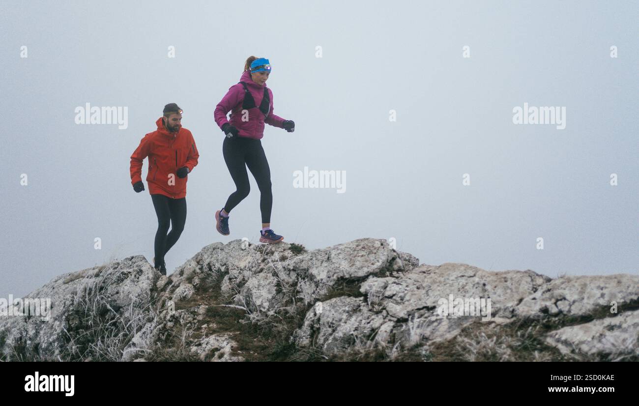 Trail running couple man and woman running on a mountain path Stock ...