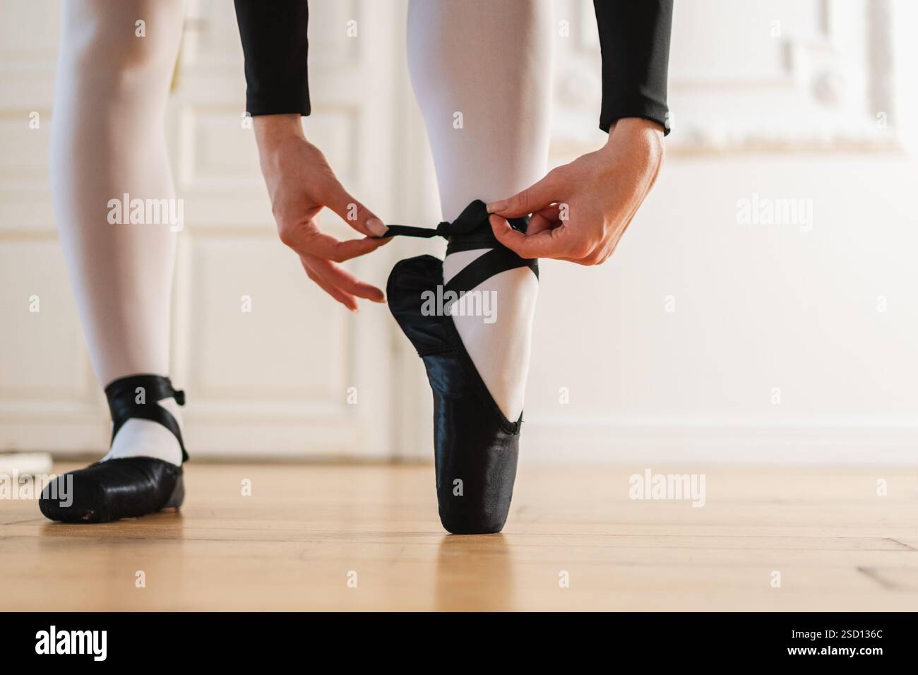 Ballerina puts on pointe shoes on leg in dance class. Classical ballet ...