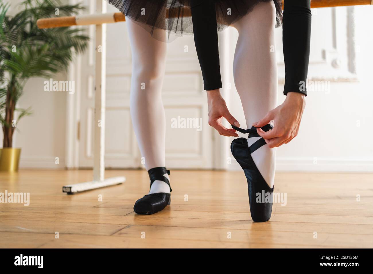 Ballerina puts on pointe shoes on leg in dance class. Classical ballet ...