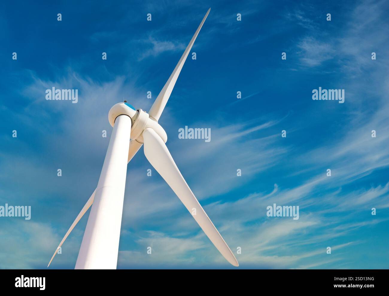 Wind turbine blade seen from below against a blue sky with white moving ...