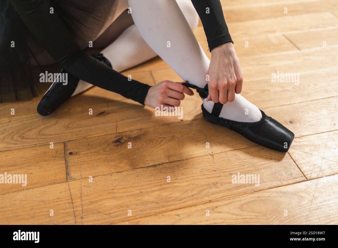 Ballerina puts on pointe shoes on leg in dance class. Classical ballet ...
