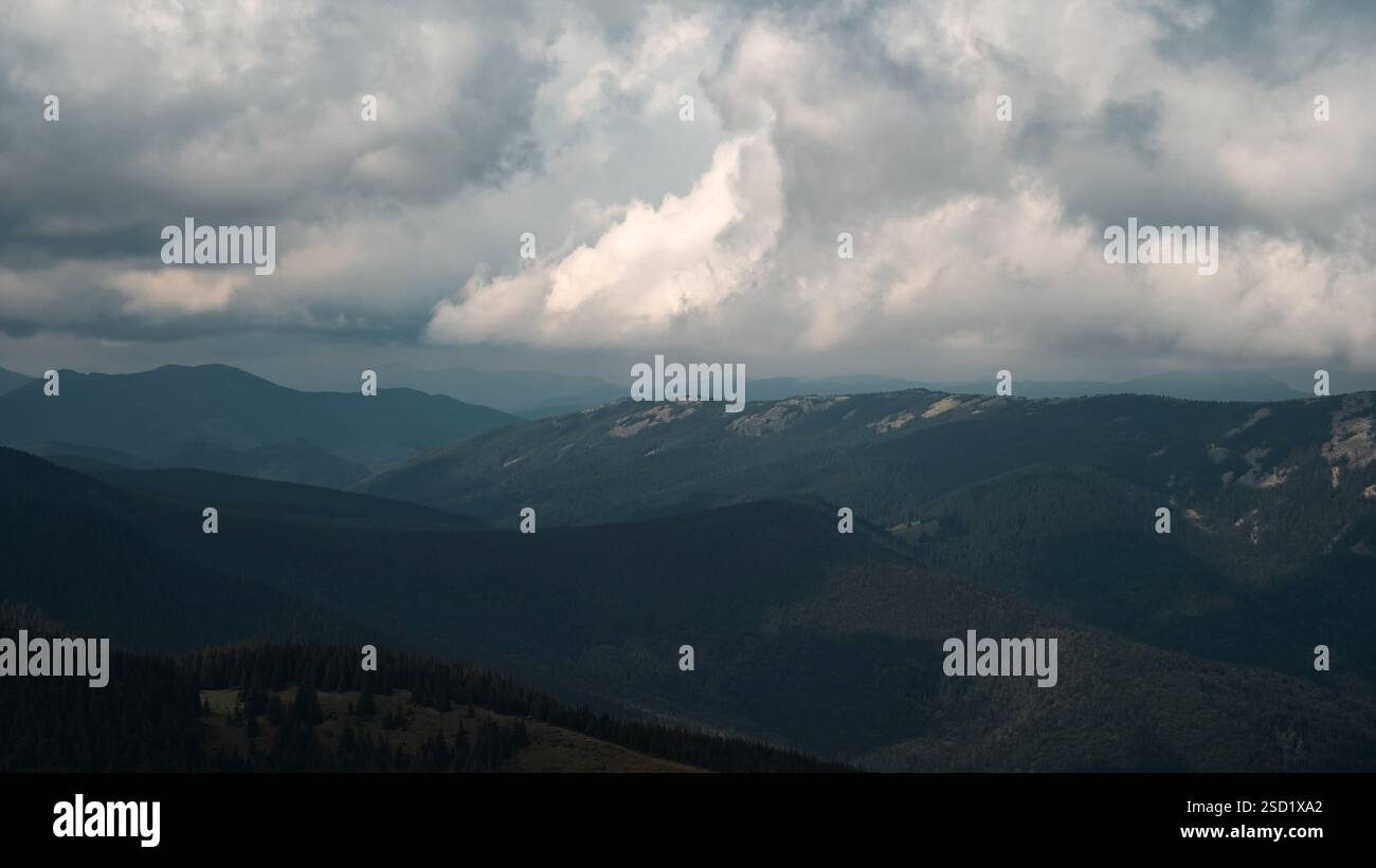 A sweeping view of rolling mountain ranges under a cloud-filled sky ...