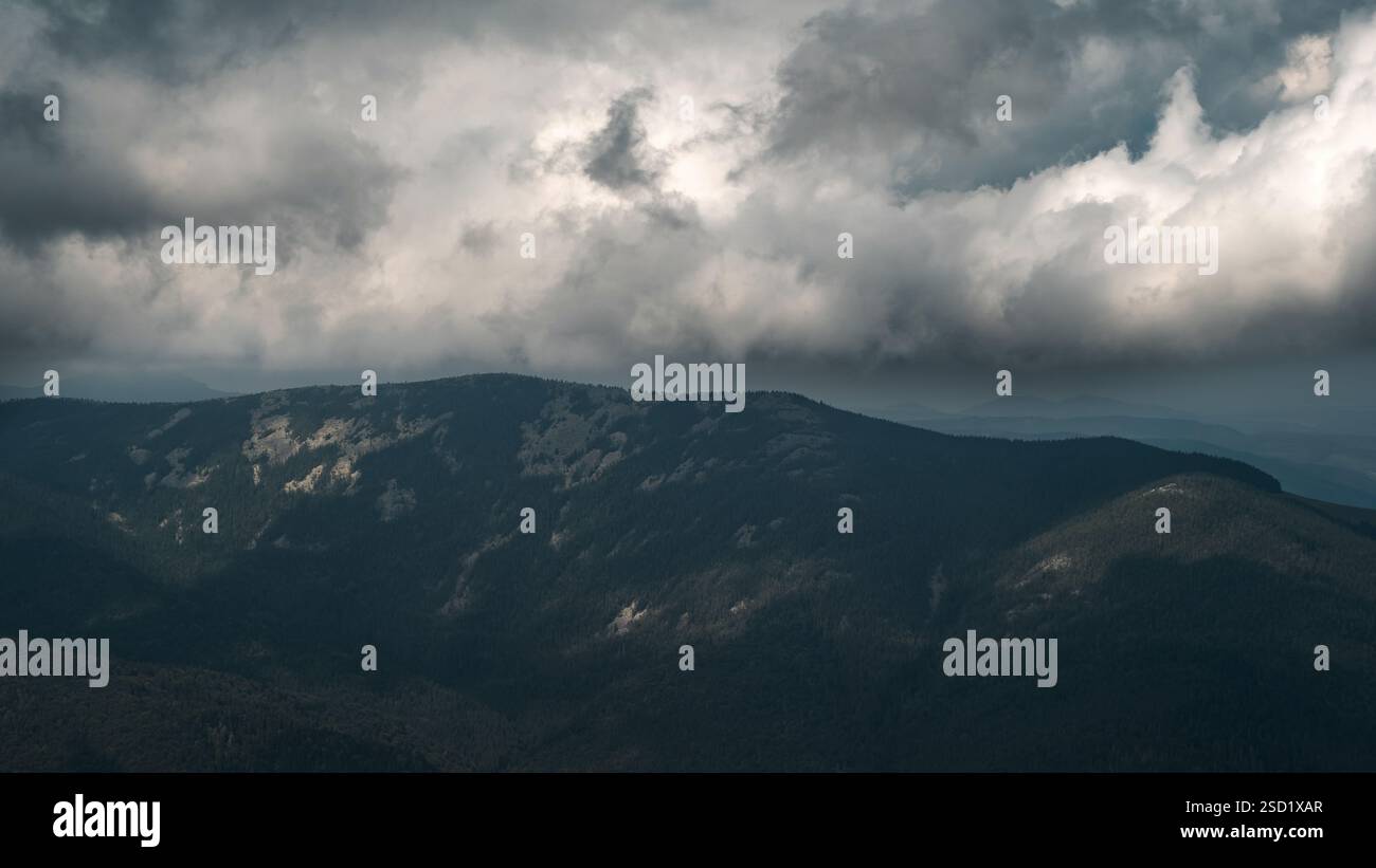 A sweeping view of rolling mountain ranges under a cloud-filled sky ...