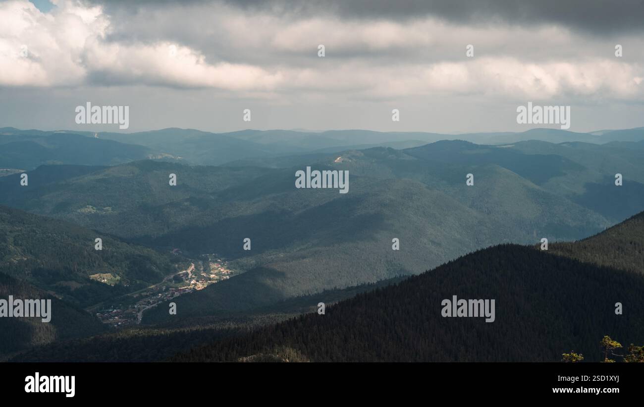 A sweeping view of rolling mountain ranges under a cloud-filled sky ...