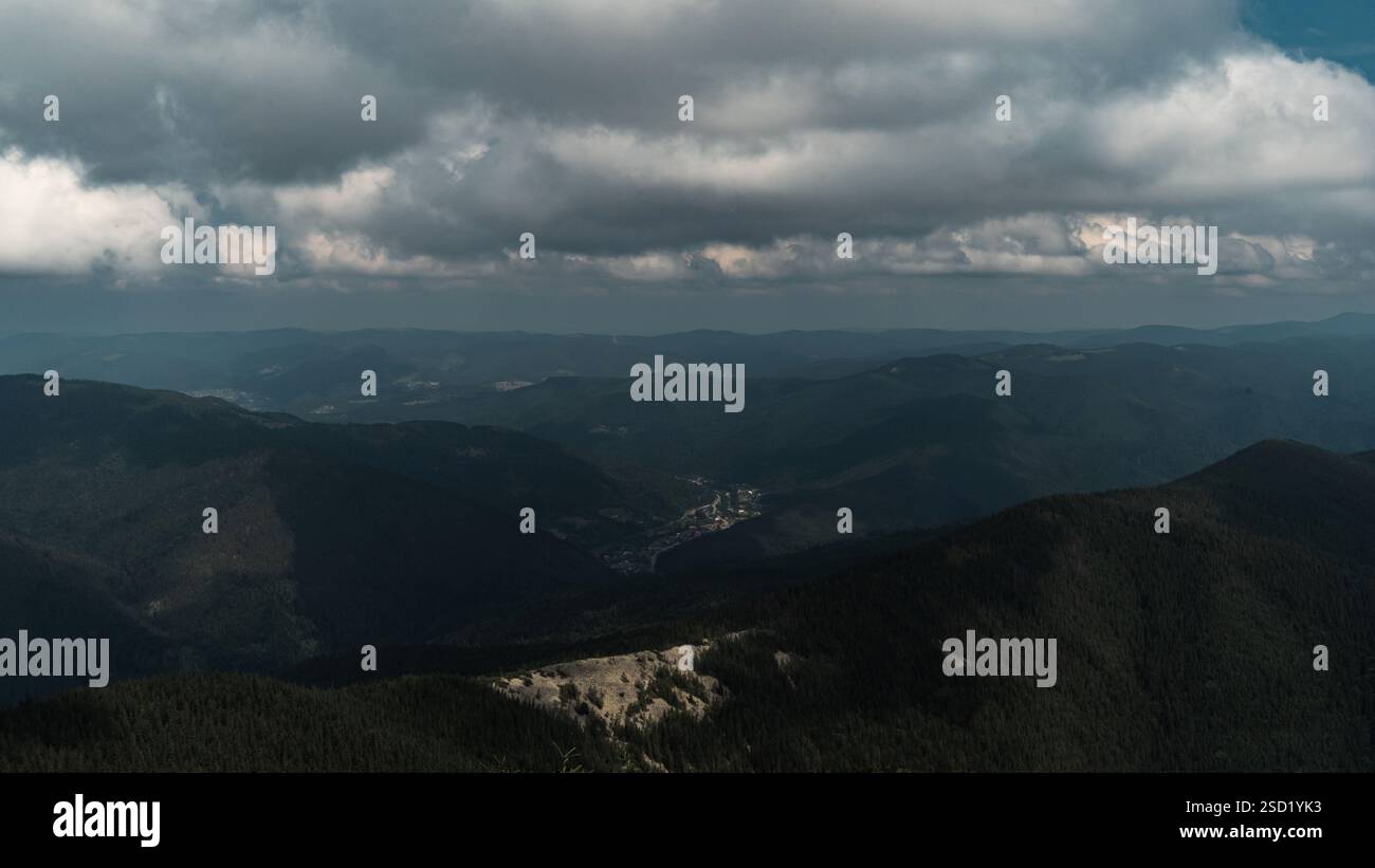 A sweeping view of rolling mountain ranges under a cloud-filled sky ...