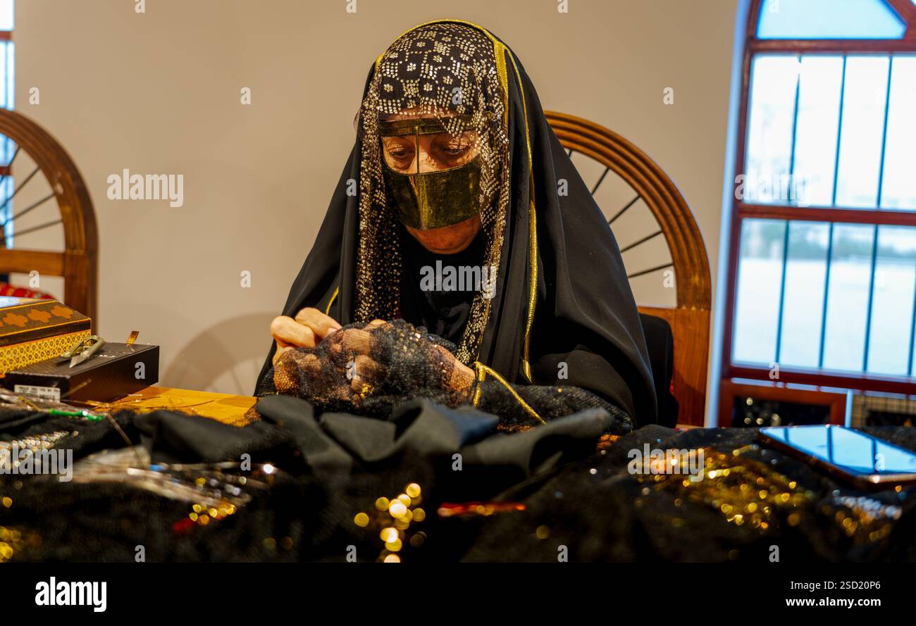 Doha, Qatar, January 28, 2025: A Qatari woman in local attire carefully ...