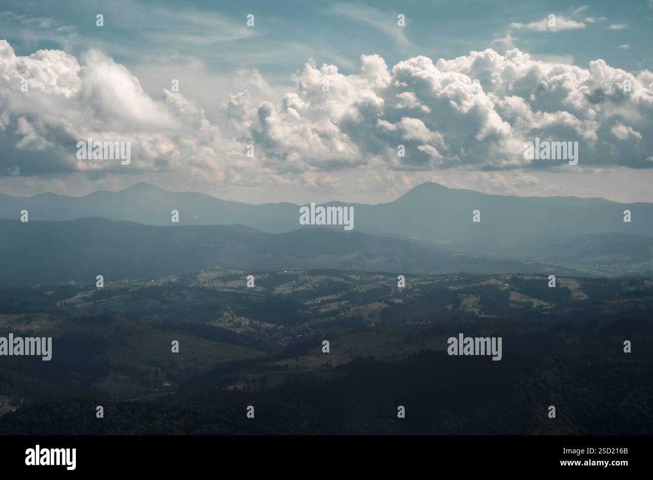 A sweeping view of rolling mountain ranges under a cloud-filled sky ...