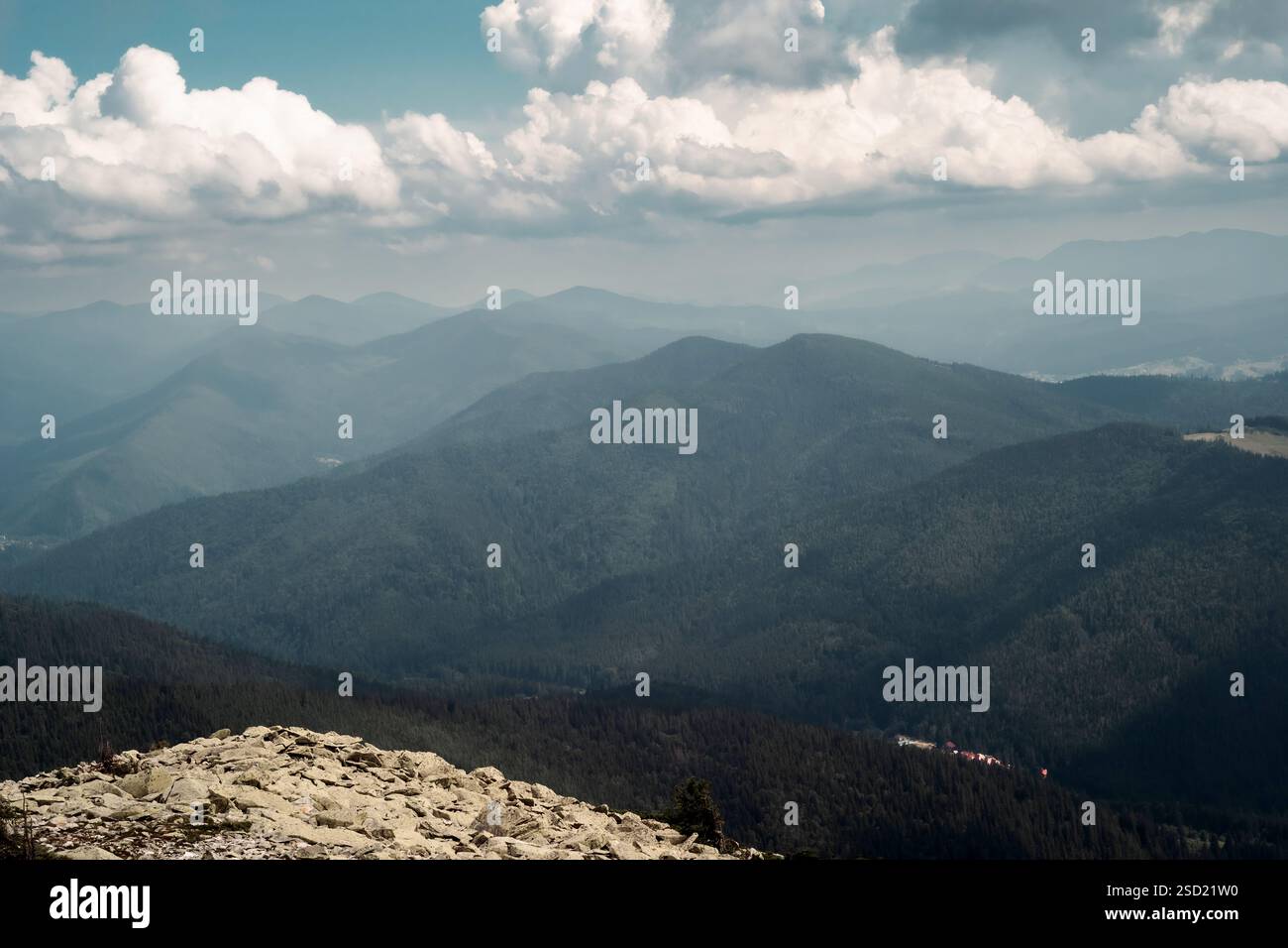 A sweeping view of rolling mountain ranges under a cloud-filled sky ...