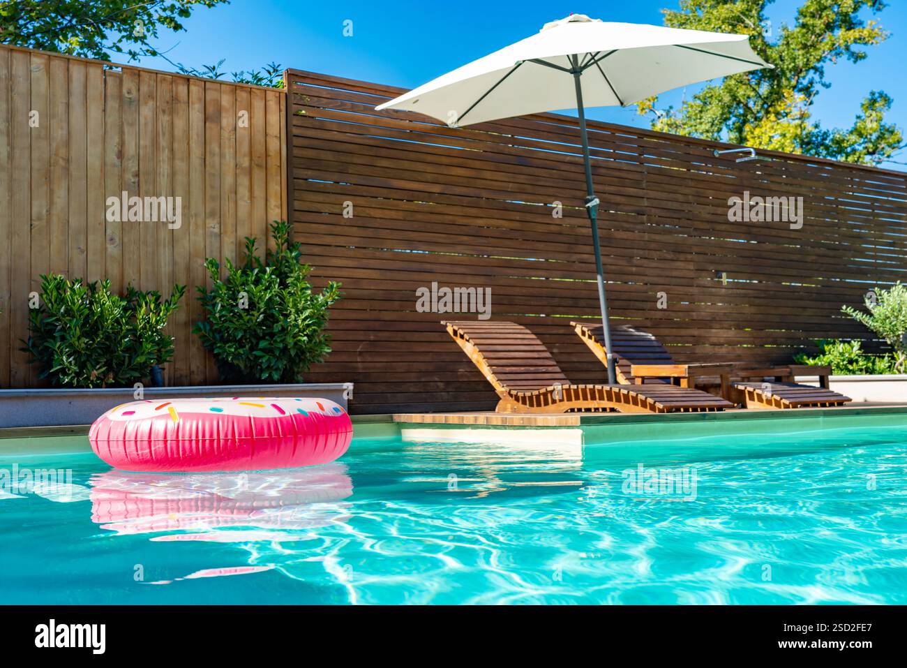Modern backyard pool with turquoise water, wooden deck, umbrella ...