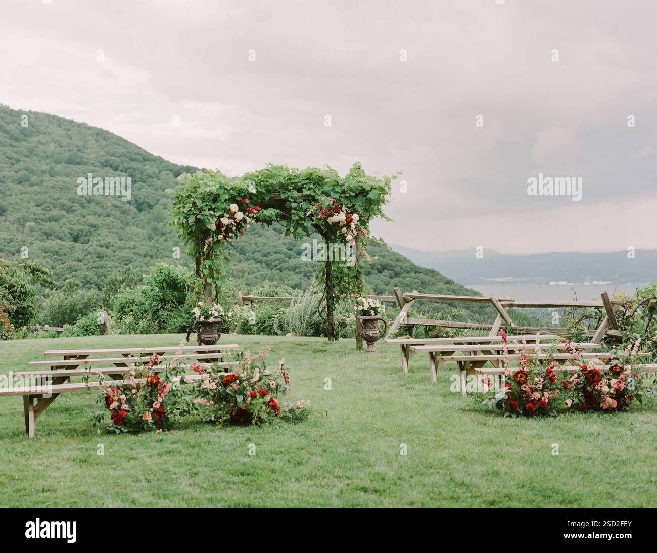 Lush green landscape with wooden benches and an arch adorned with ...