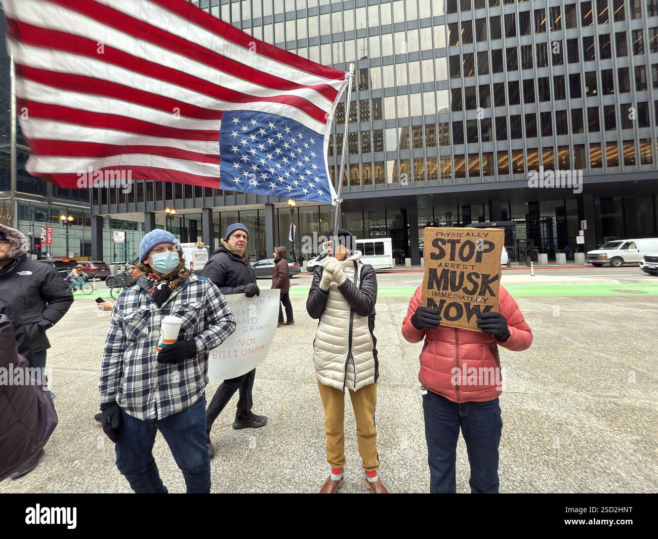 Woman holding upside down flag, another holding Stop Musk Now sign at ...