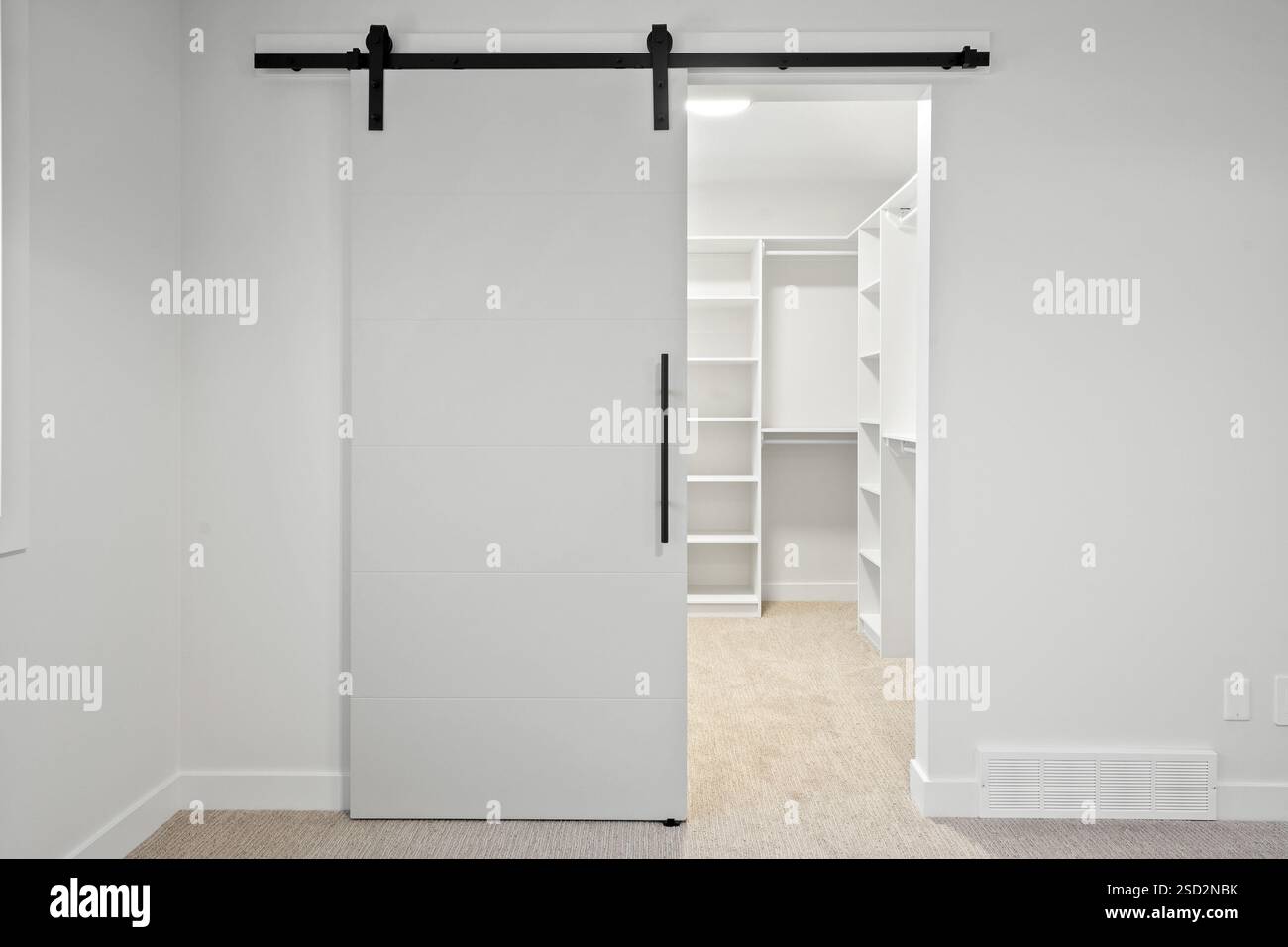 White door with a black handle is in front of a white closet. The ...