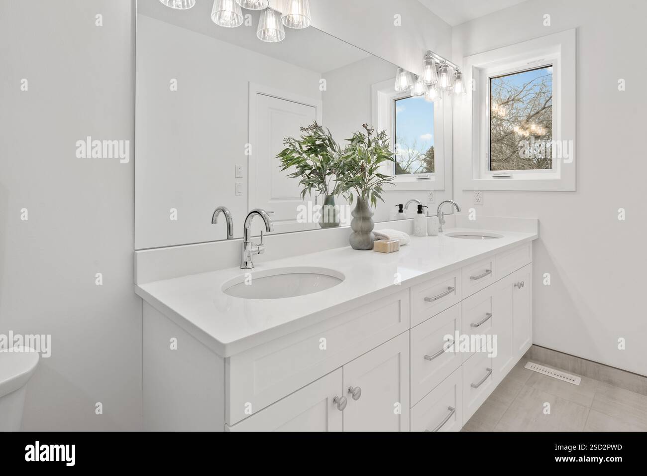 The bathroom is clean and well-lit, with a large mirror and a window ...