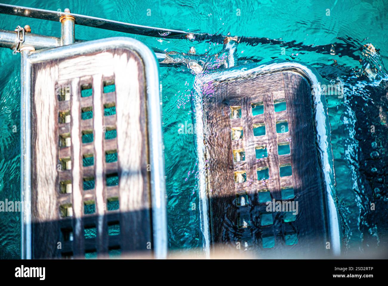 A detailed close-up of a weathered wooden ladder extending over the sea ...