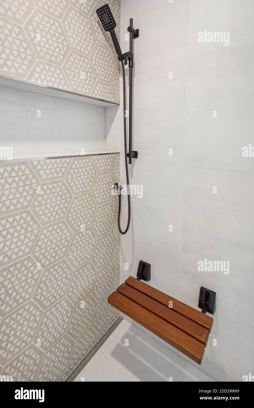 Bathroom with a wooden bench and a black shower head. The bench is ...