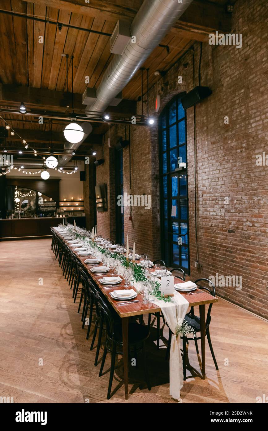 Long dining table set for a gathering in a rustic venue, featuring ...
