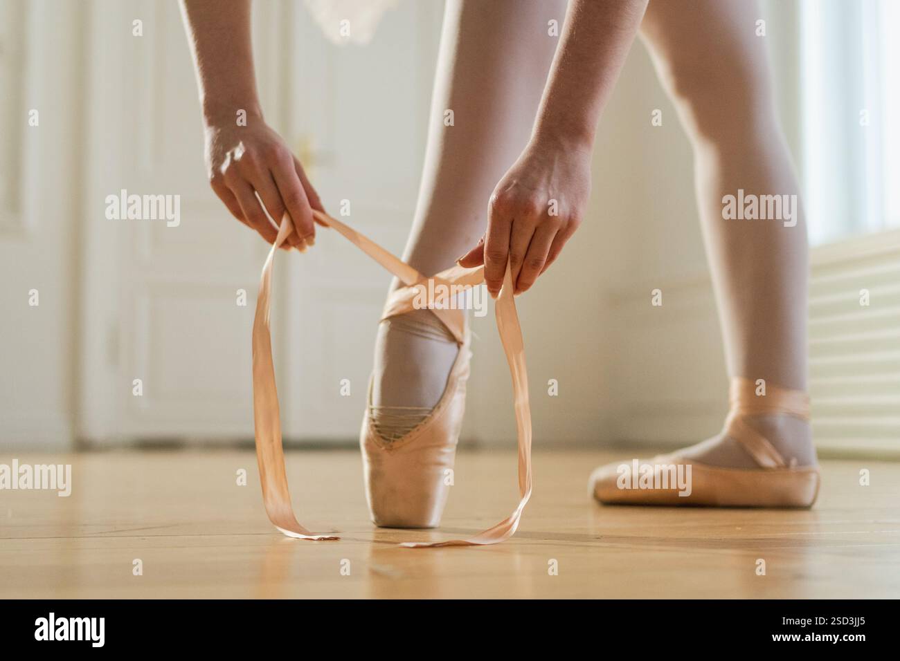 Ballerina puts on pointe shoes on leg in dance class. Classical ballet ...