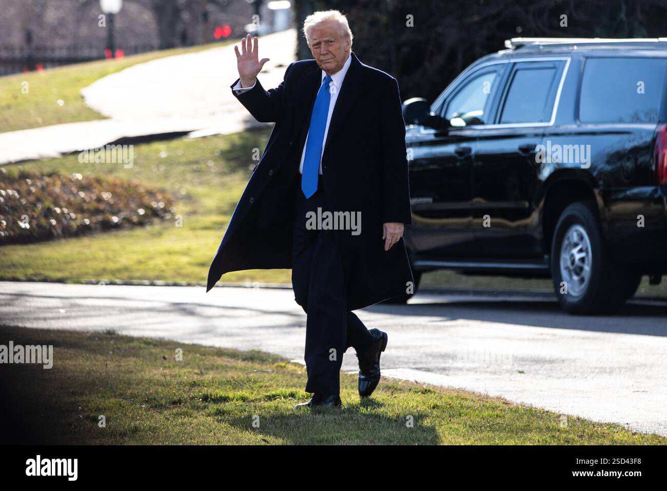 US President Donald Trump waves as he departs the Oval Office, boarding ...