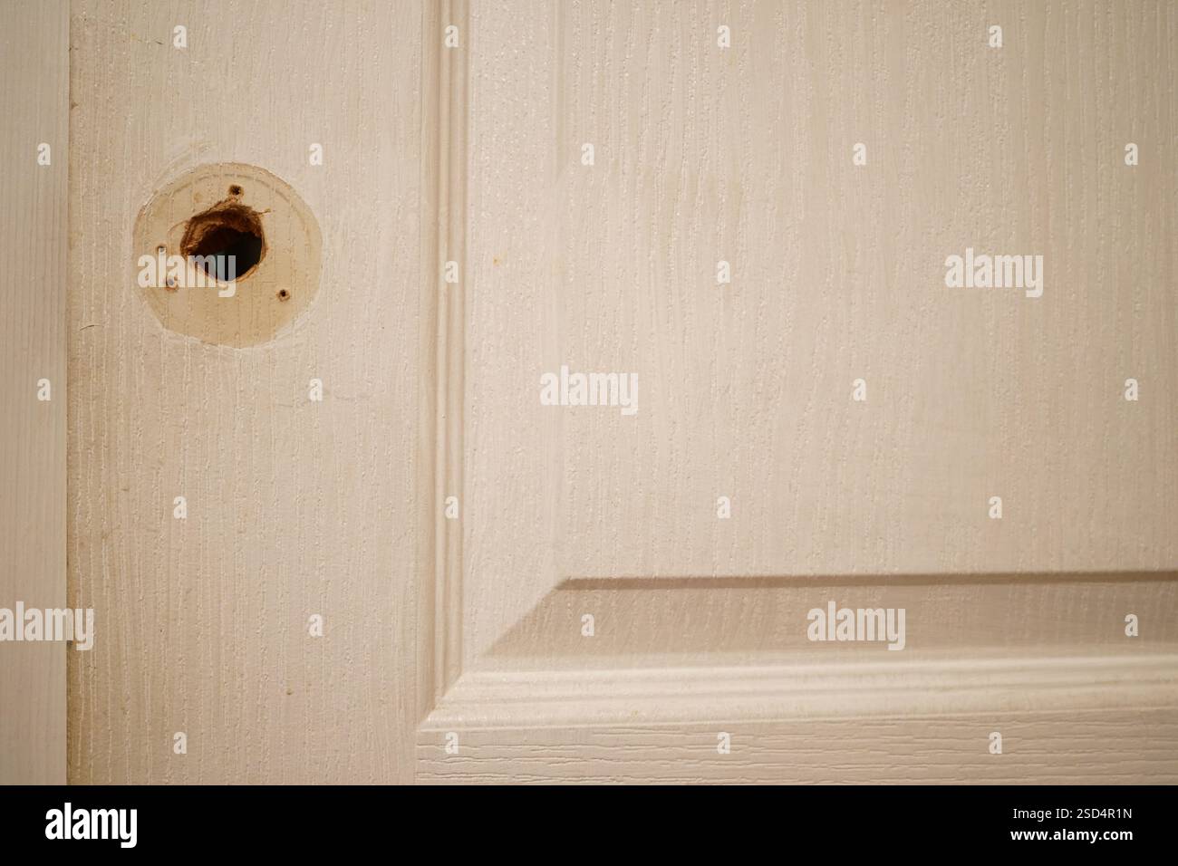 A residential door shows signs of wear with a missing knob and a worn ...