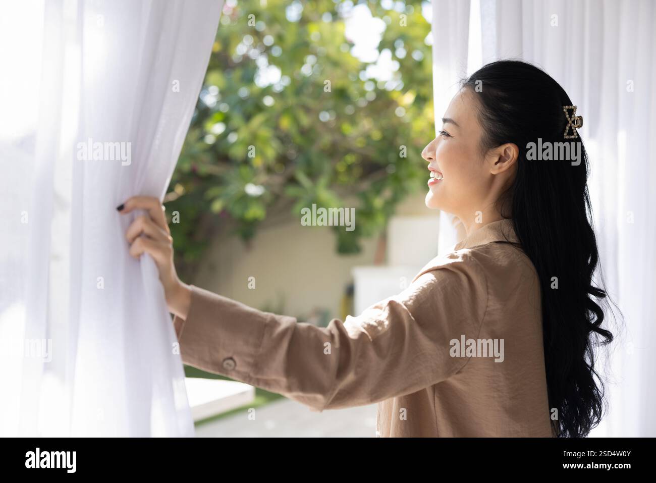 Happy Asian homeowner woman opening white veils at window Stock Photo ...