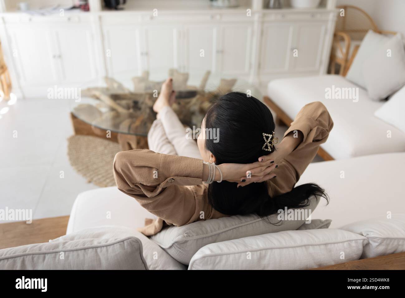 Back view of young Asian homeowner woman resting on couch Stock Photo ...
