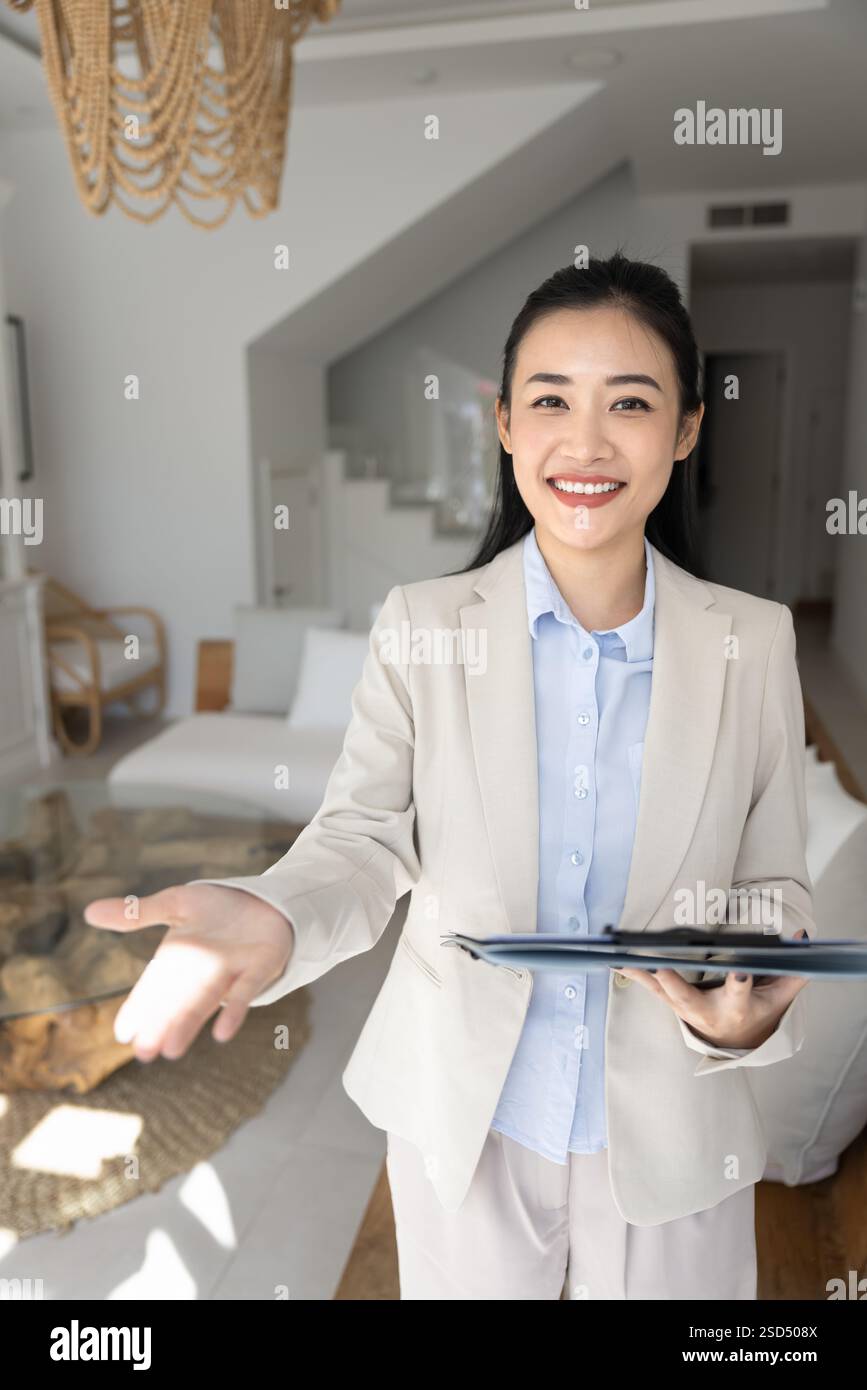 Happy young Asian professional realtor woman making inviting hand ...