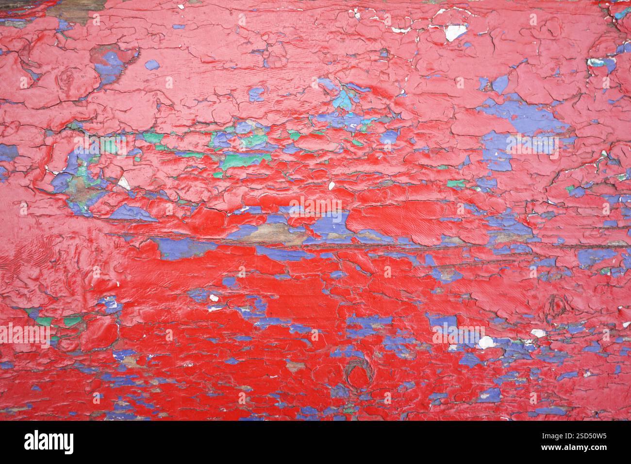 A close-up view reveals layers of bright red paint peeling away to ...