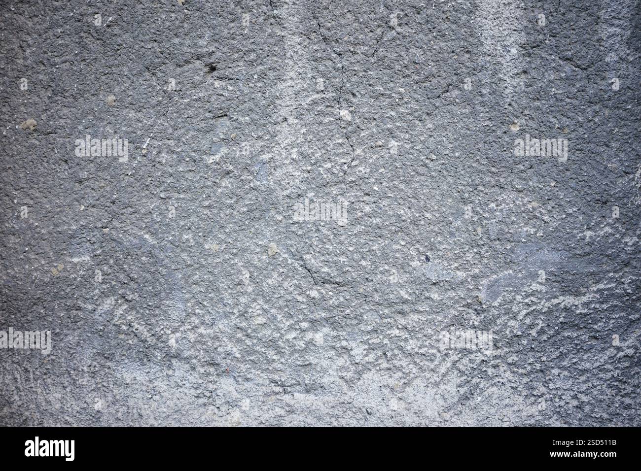 A gray concrete wall features a rough texture and subtle patterns. The ...