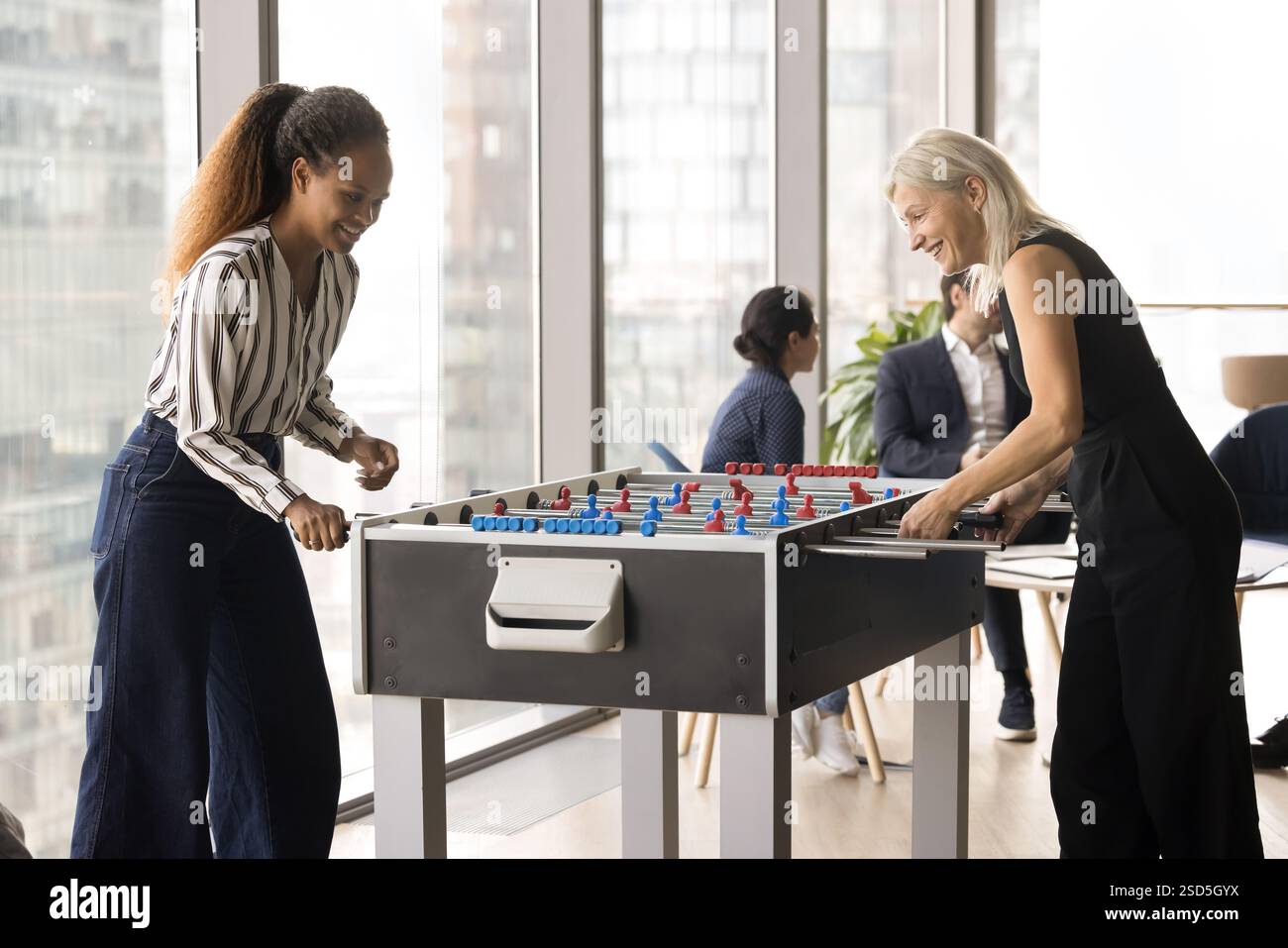 Two multiethnic women colleagues playing foosball game Stock Photo - Alamy