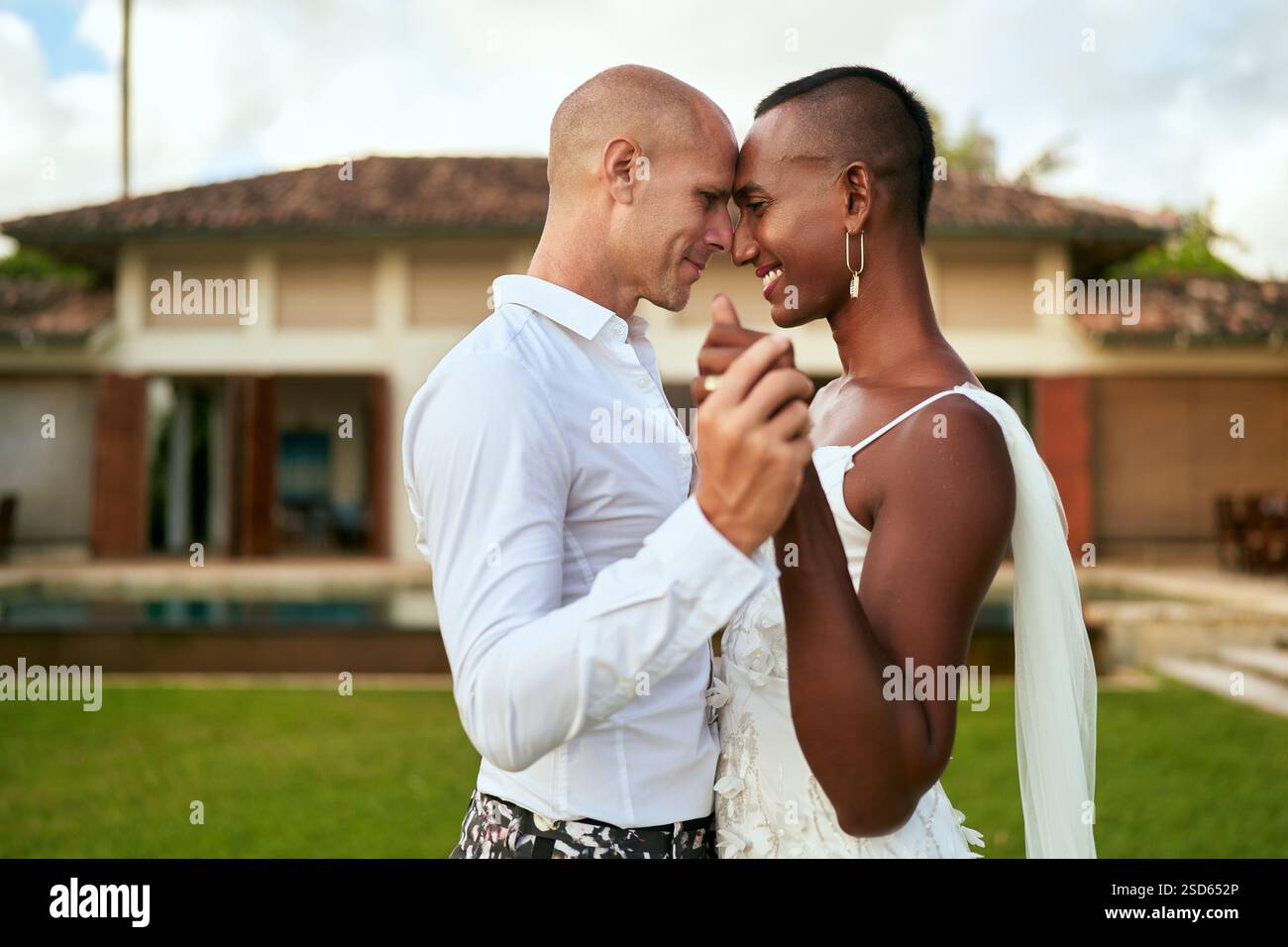 LGBTQ couple dances in villa wedding. Bride in white dress, groom in ...